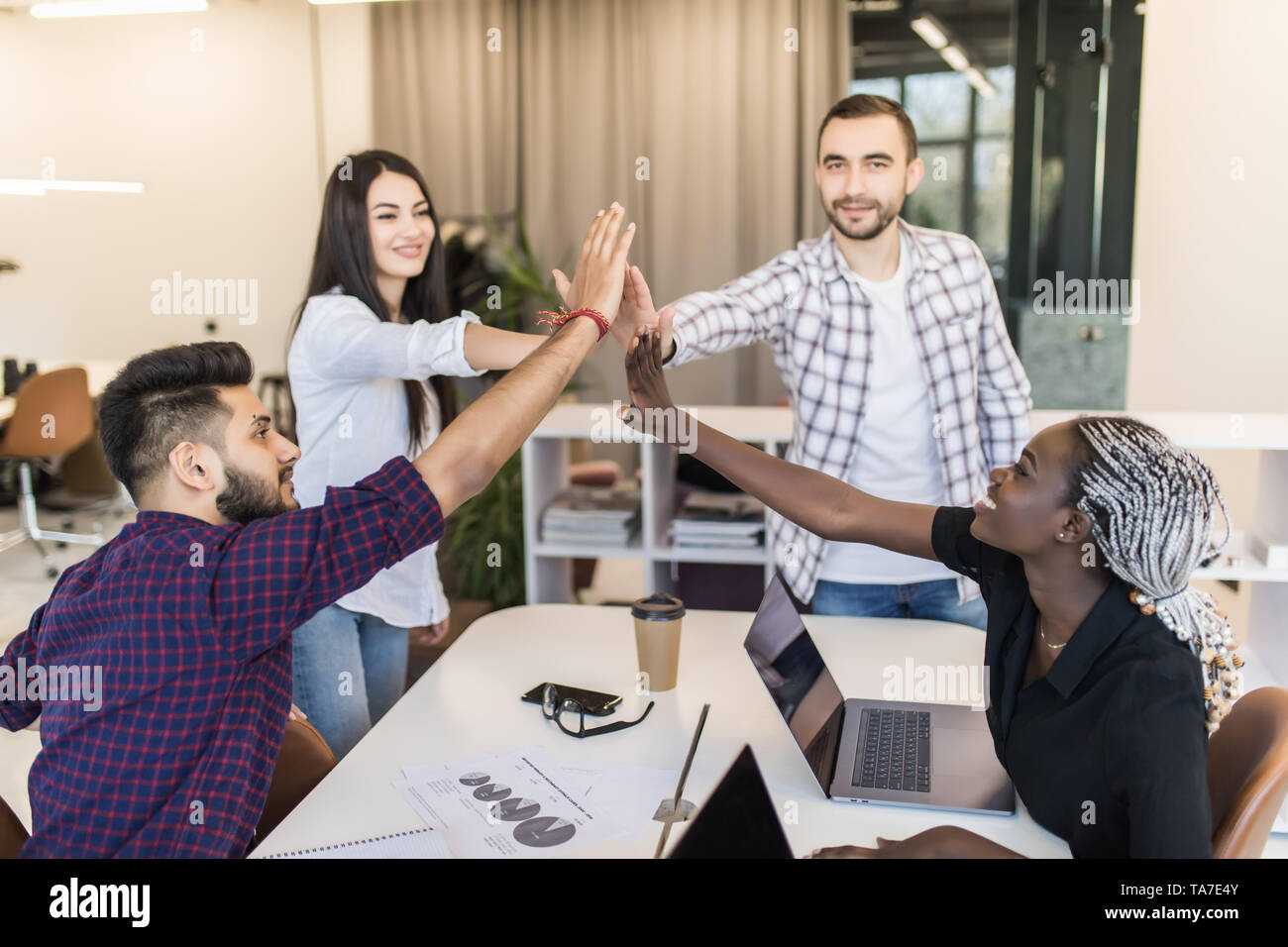 Successful business team is giving high five and smiling while standing ...