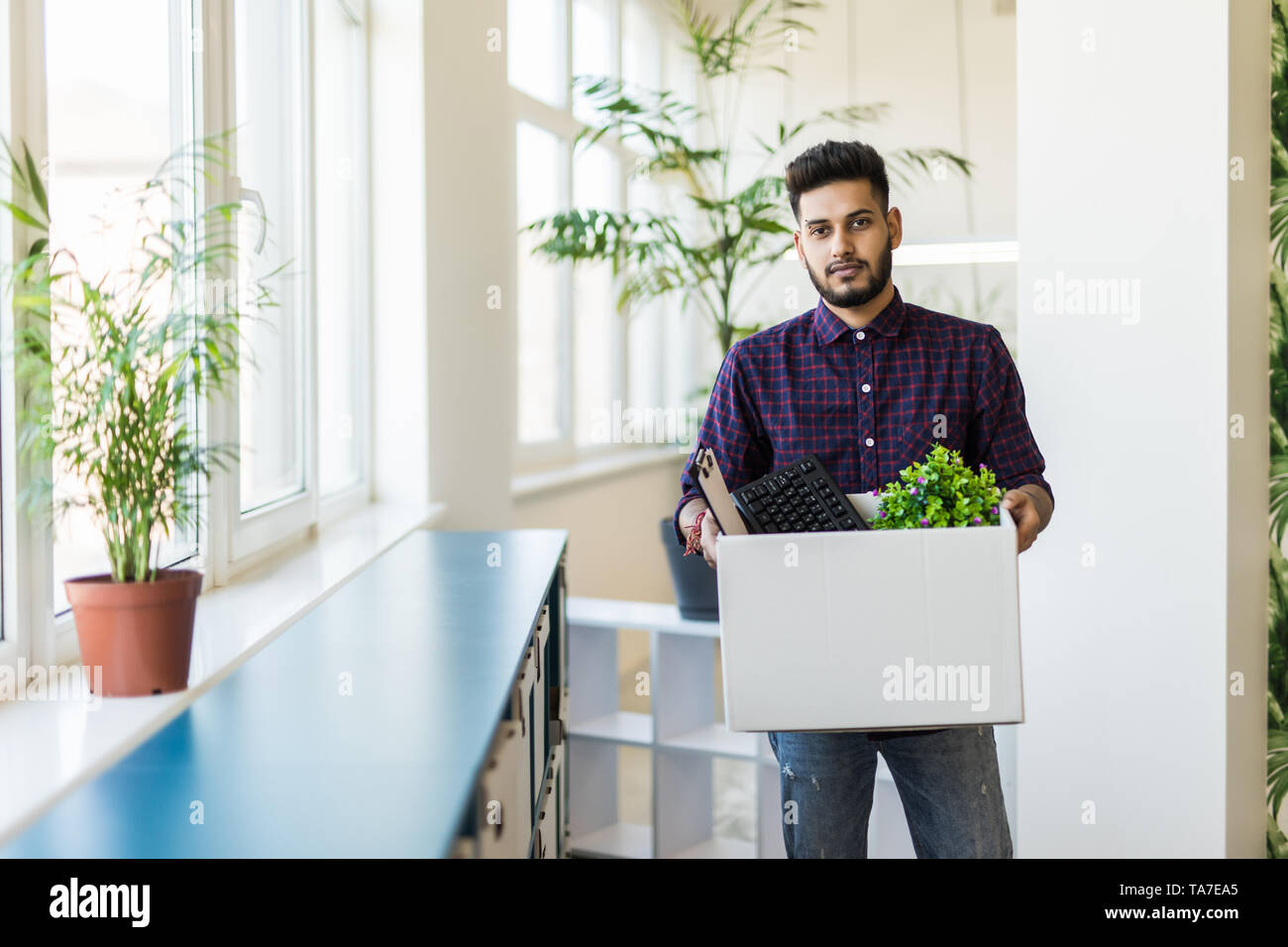 Shot of a young professional man carrying cardboard box into his hand ...