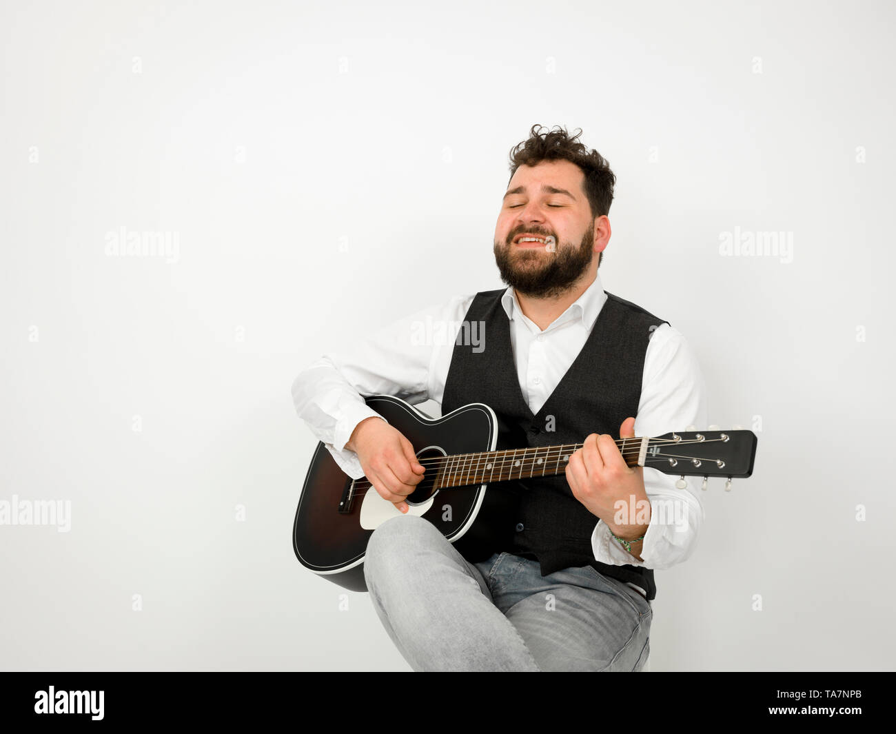 man with black hair and beard playing and singing with acoustic guitar ...