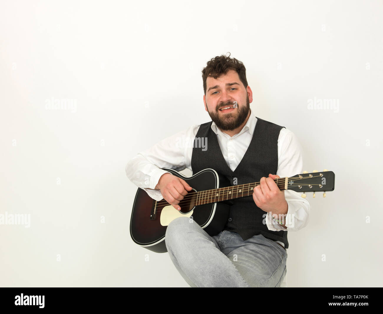 man with black hair and beard playing and singing with acoustic guitar ...