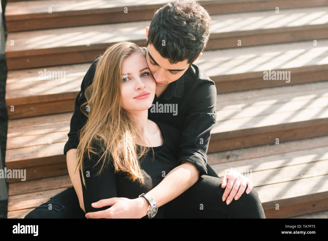 Beautiful young multiracial couple, student couple in love, sit wooden ...