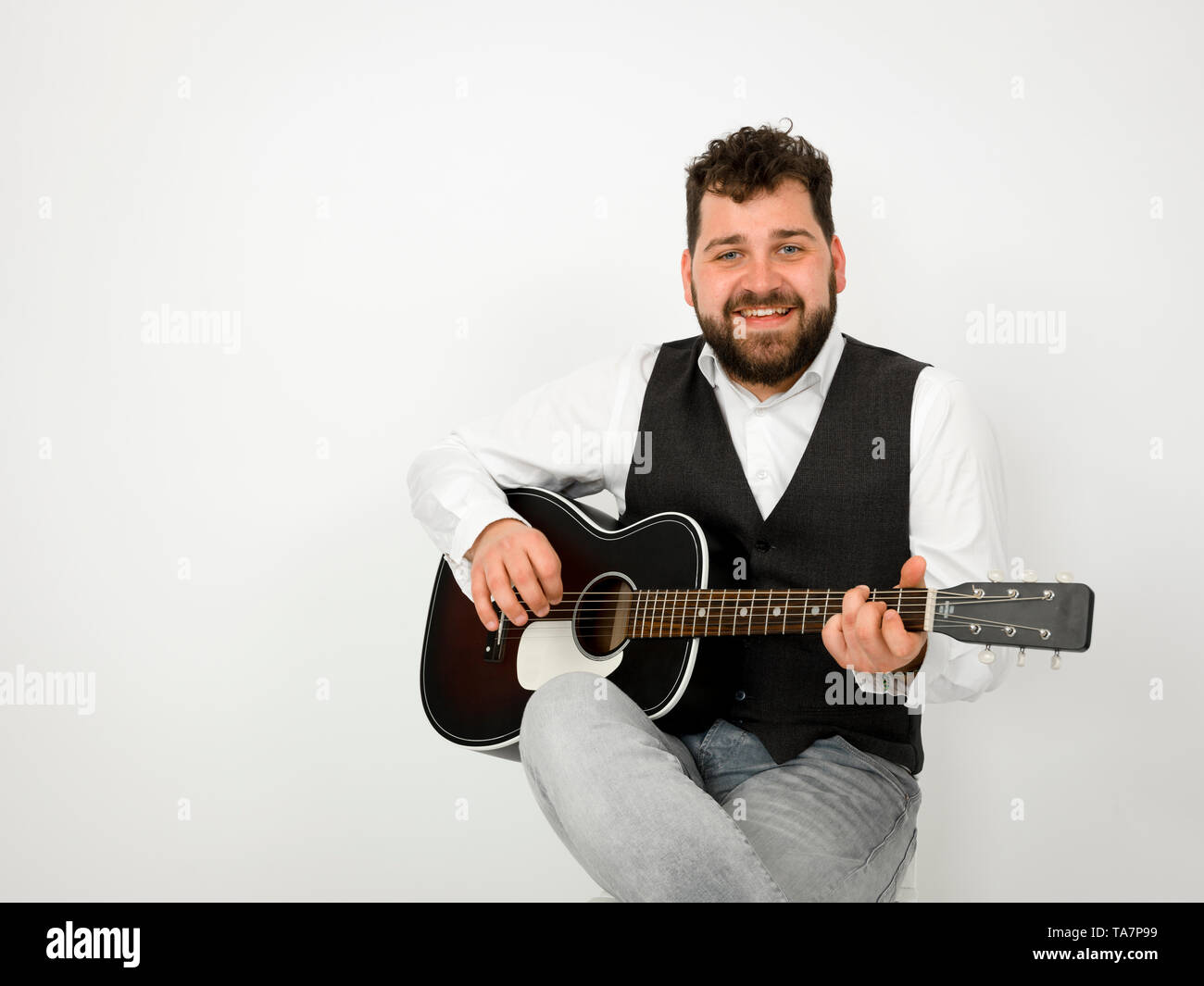 man with black hair and beard playing and singing with acoustic guitar ...