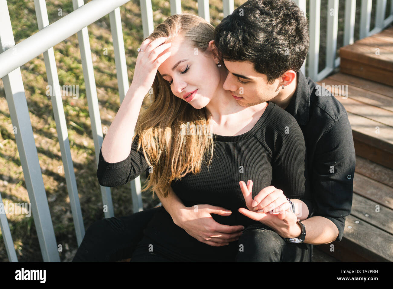 Beautiful young multiracial couple, student couple in love, sit wooden ...