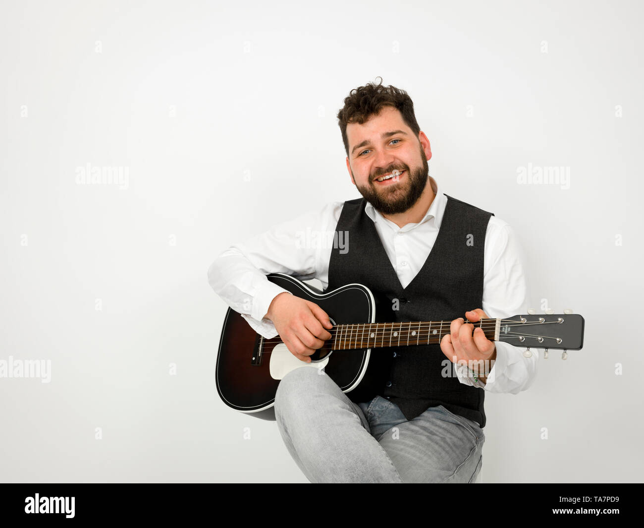 man with black hair and beard playing and singing with acoustic guitar ...