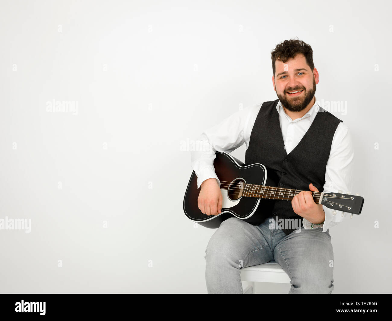 man with black hair and beard playing and singing with acoustic guitar ...