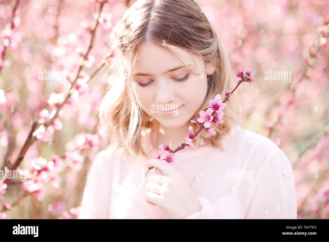 Beautiful smiling blonde girl 16-17 year old posing in peach flowers ...