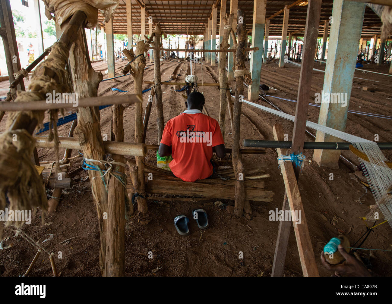 African man from Senufo tribe weaving in a traditional textile factory ...