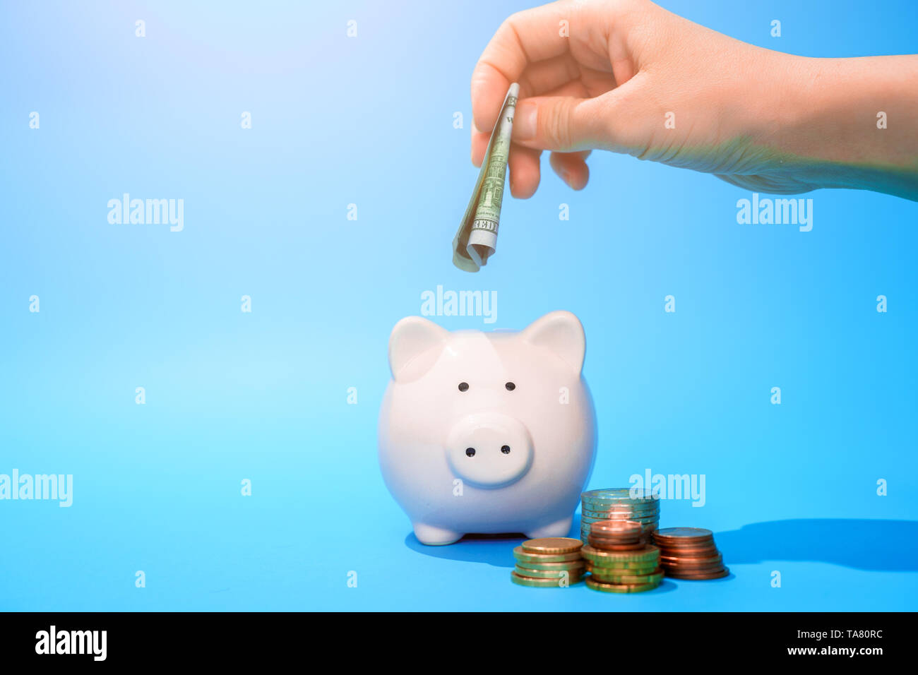 Photo of hand of man putting money into piggy bank on blue empty ...