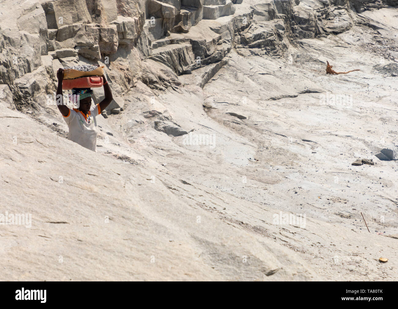 African woman carrying stones in a granite quarry, Savanes district ...