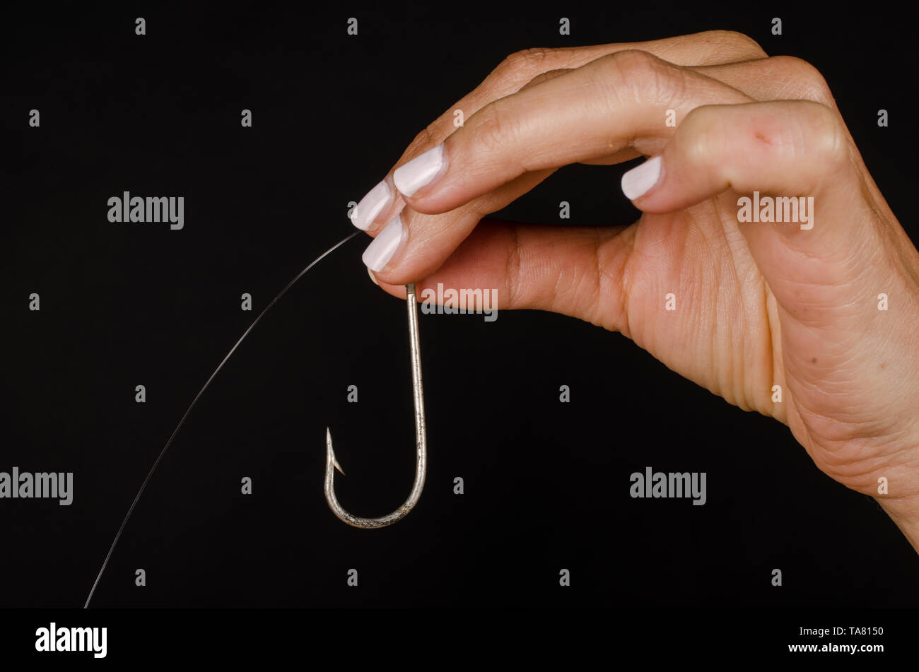 Female hand holding a fishing hook, a conceptual shot on risks and ...
