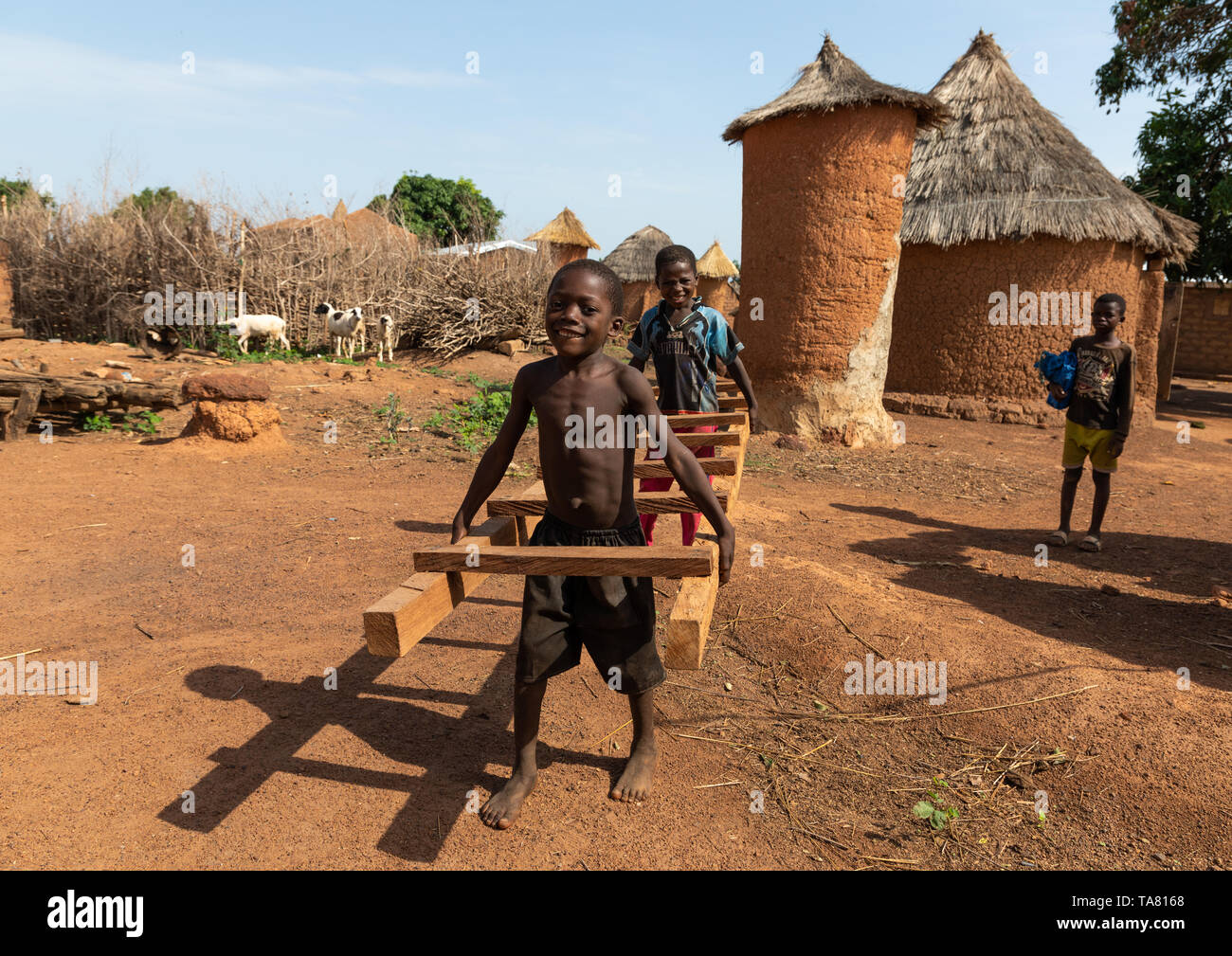 African children carrying a ladder in front of granaries, Savanes ...