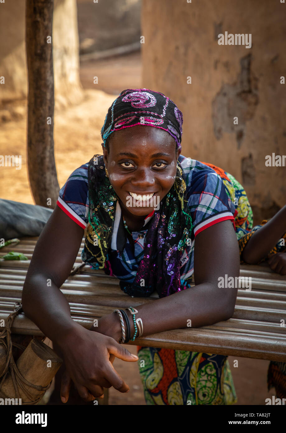 Portrait of a Dan tribe smiling woman resting on a wood bed, Bafing ...