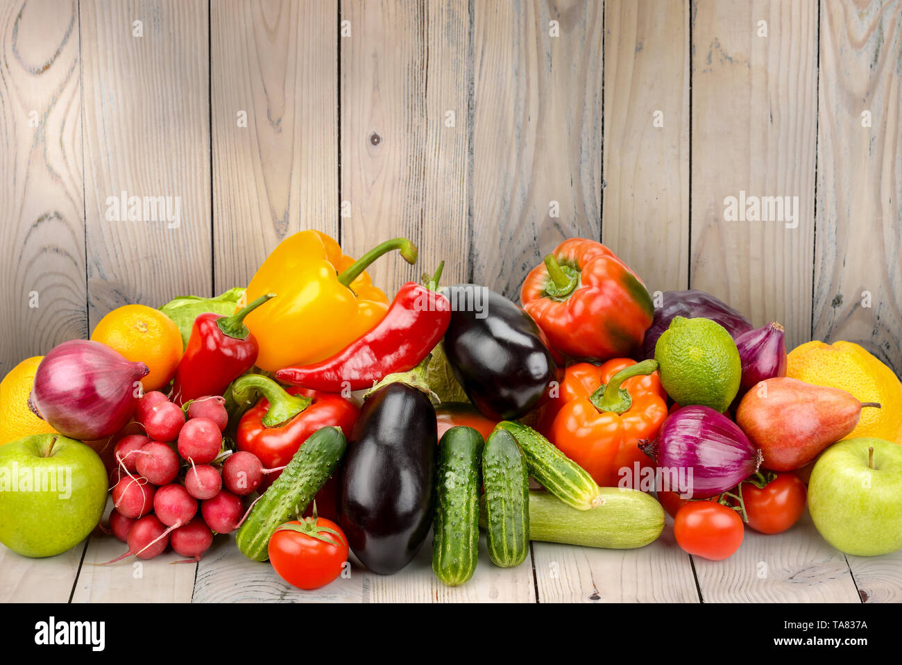Pile fruits and vegetables on wooden table on background wooden wall ...