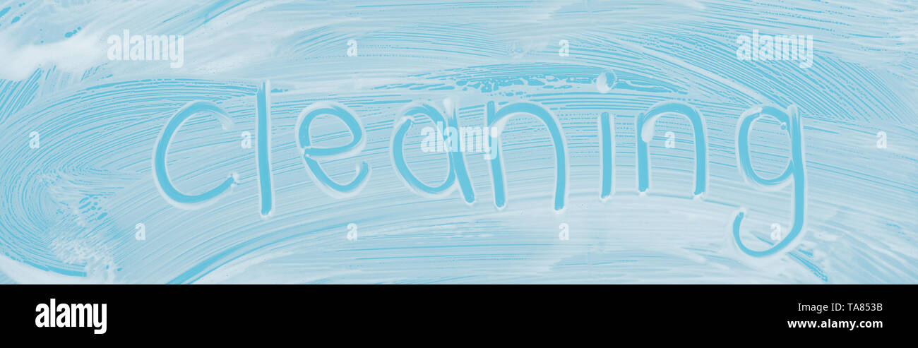 panoramic shot of glass covered with white foam on blue background with ...