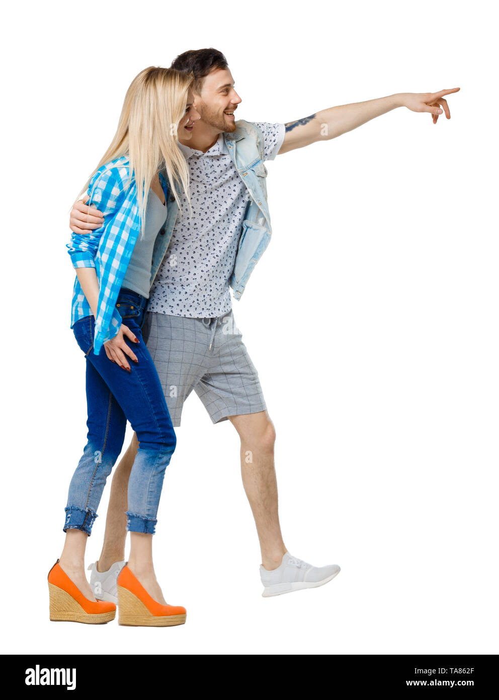 Side view of the couple walking and pointing upwards. Rear view people ...