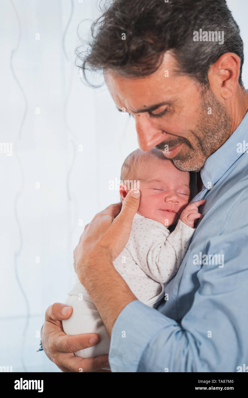 New father sleeping his cute adorable newborn on his lap. Baby ...