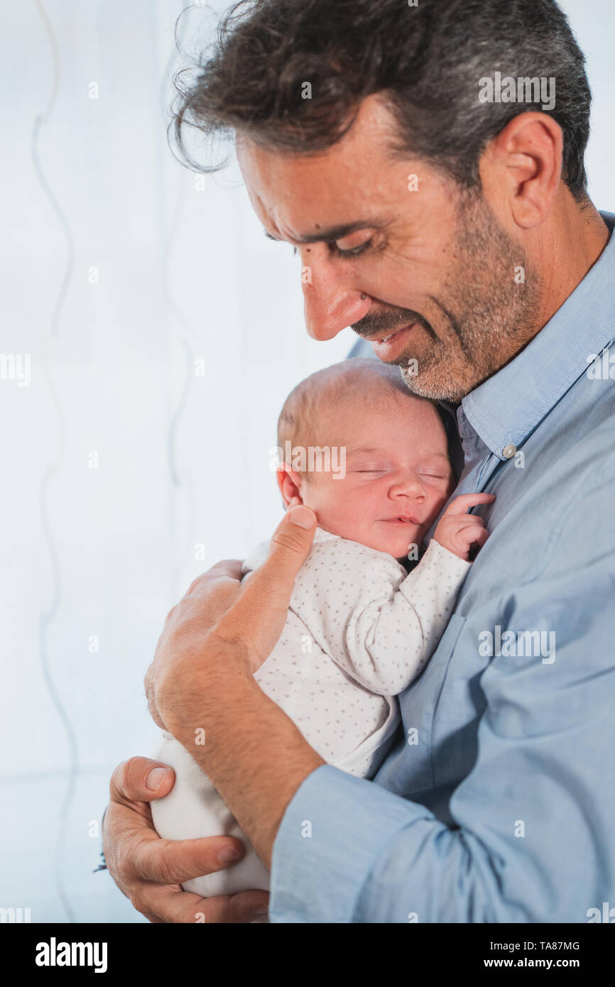 New father sleeping his cute adorable newborn on his lap. Baby ...