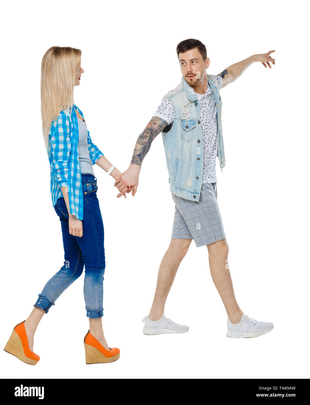 Side view of the couple walking and pointing upwards. Rear view people ...