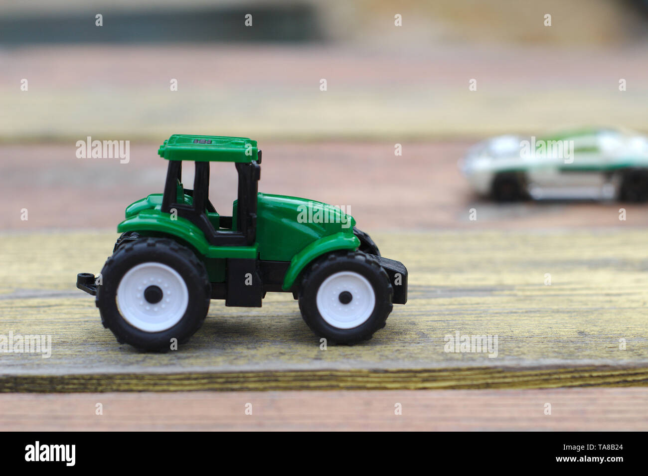 toy green tractor on a yellow-red wooden table Stock Photo - Alamy