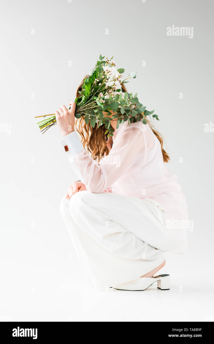 Girl Covering Face With Flowers With Green Eucalyptus Leaves While