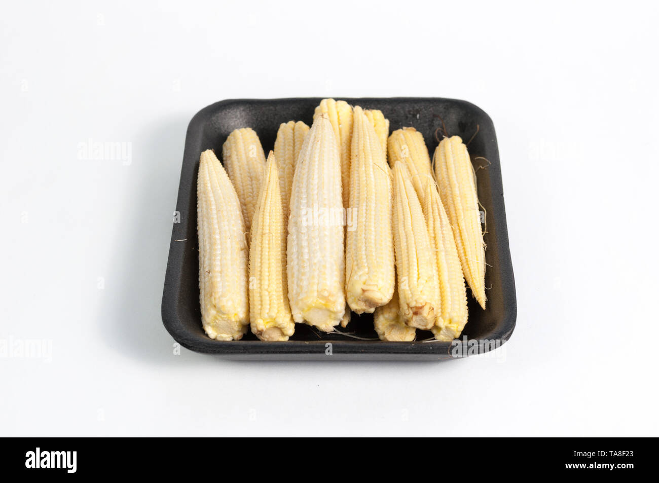 Close up baby corn in foam pack supermarket isolated on white ...