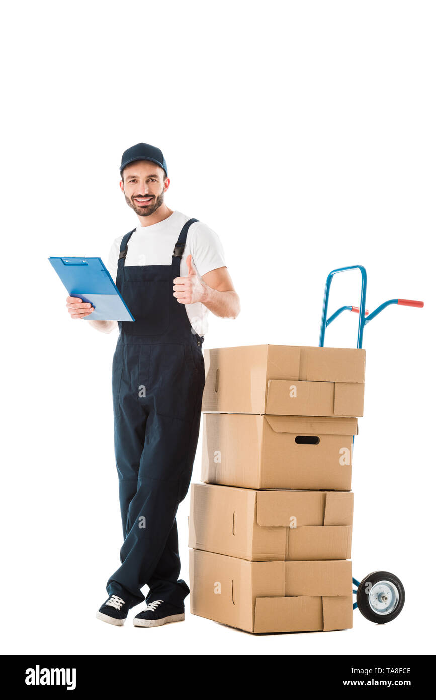 happy delivery man standing near hand truck with carton boxes and ...