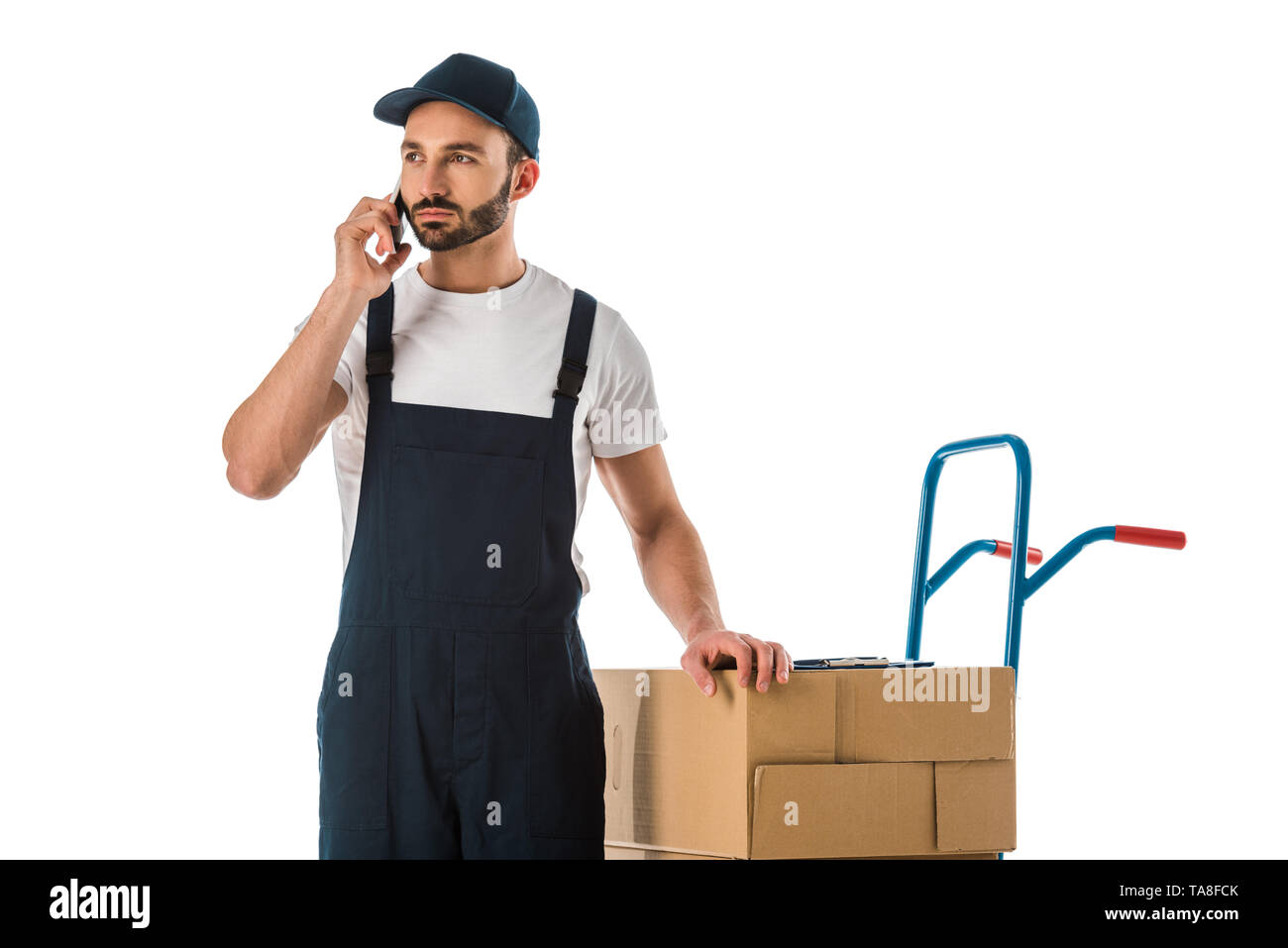 serious delivery man talking on smartphone while standing near ...