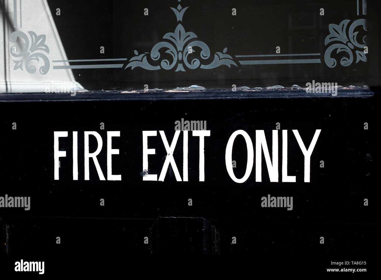 emergency fire exit only sign on black painted timber door to retail ...