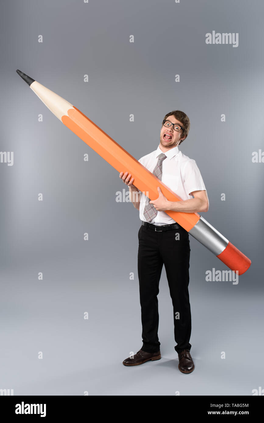 funny businessman in glasses holding huge and heavy decorative pencil ...