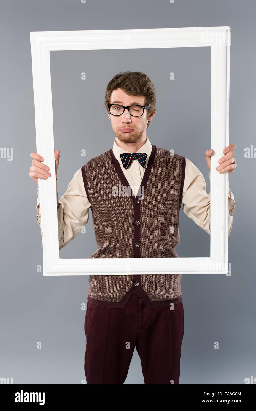man in glasses winking and holding white frame on grey background Stock ...