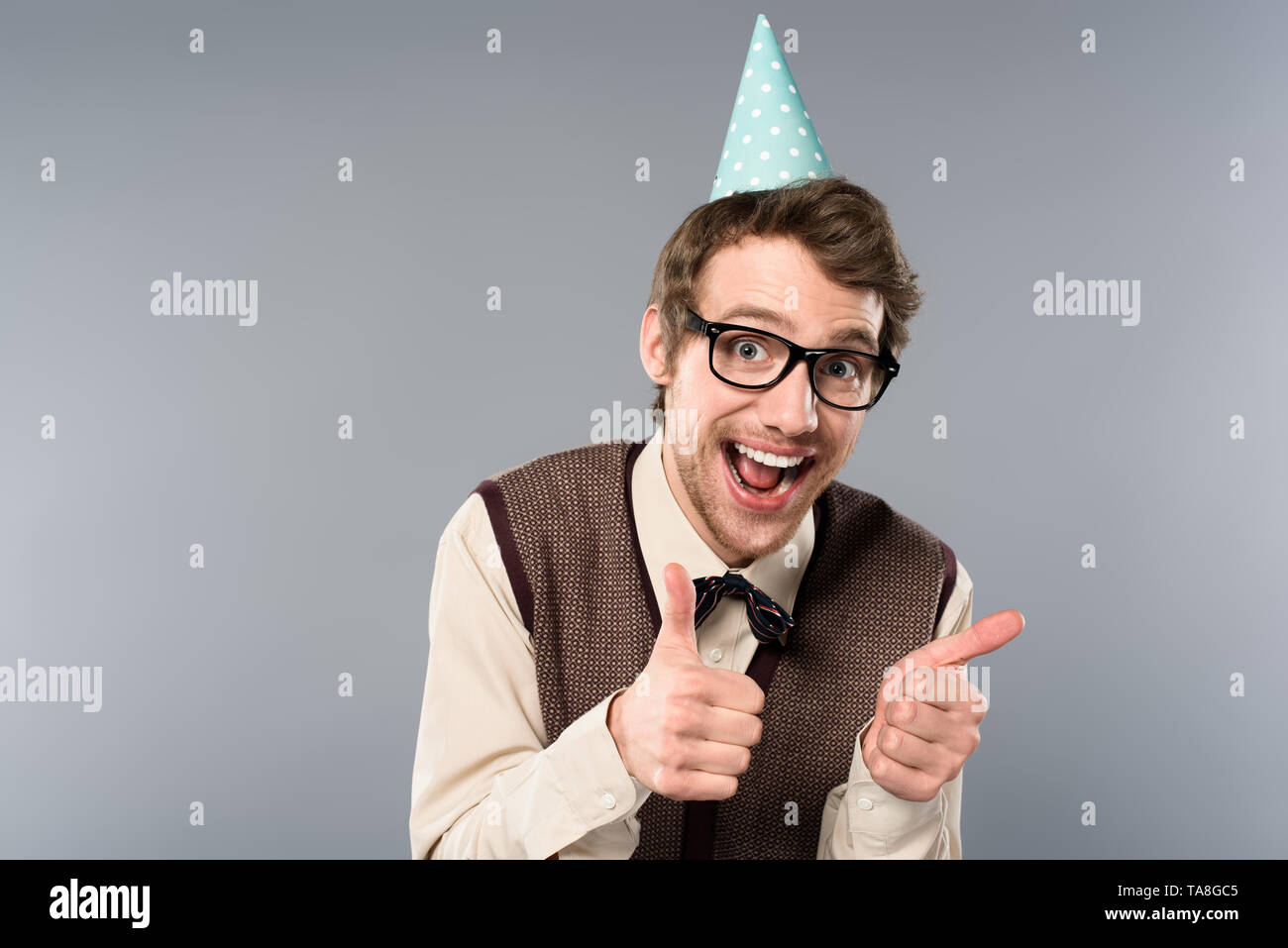excited man in party cap showing thumbs up Stock Photo - Alamy