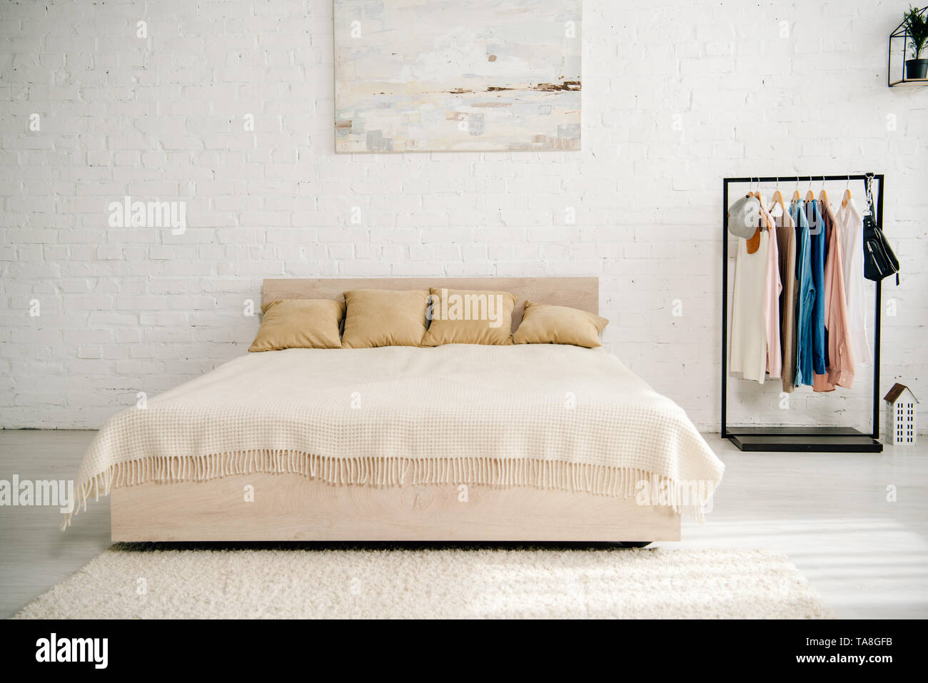 Light bedroom with big bed, carpet and straight rack Stock Photo - Alamy