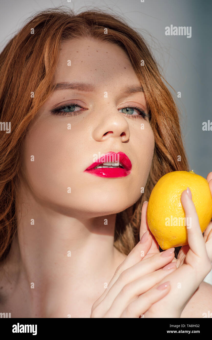 Beautiful Redhead Girl With Red Lips Posing With Lemon And Looking At