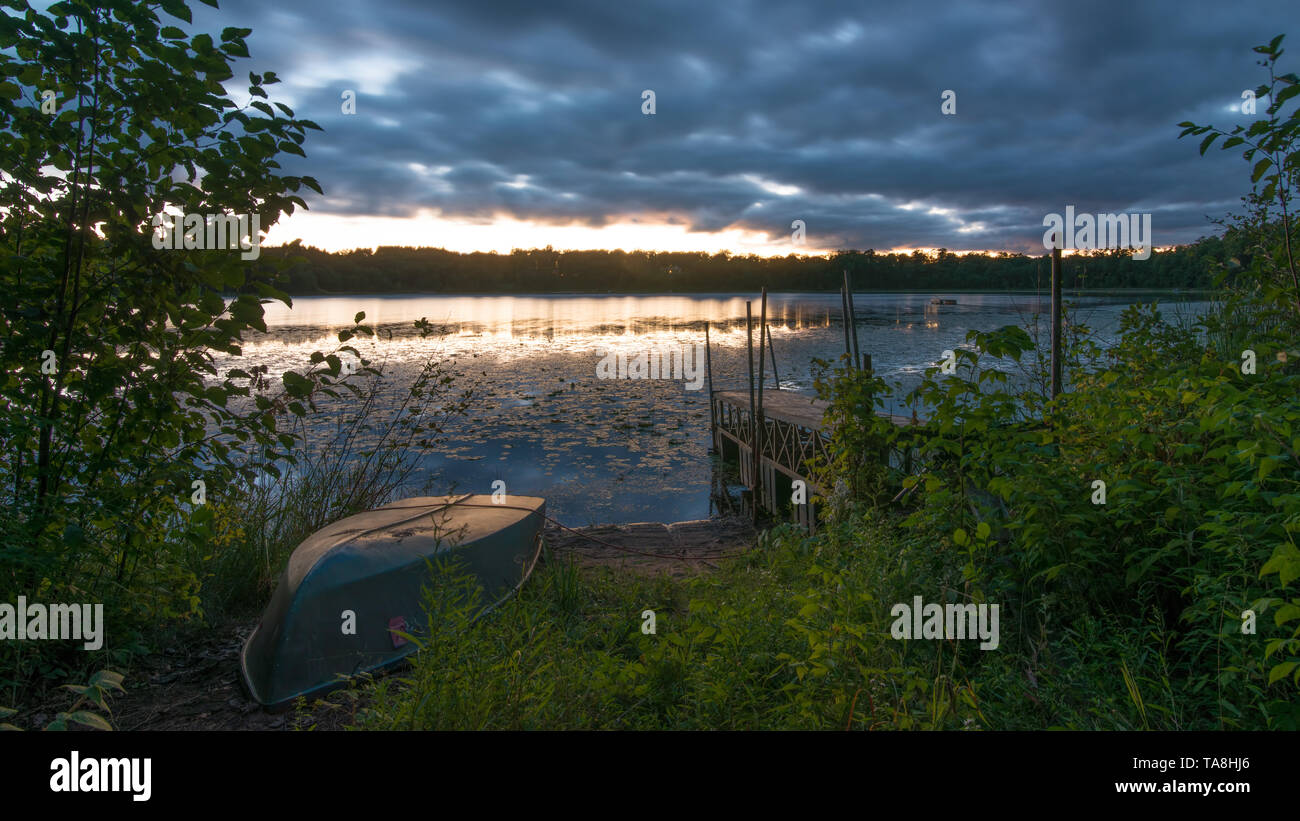 Sunset with old dock and old row boat on small remote lake in Northern ...