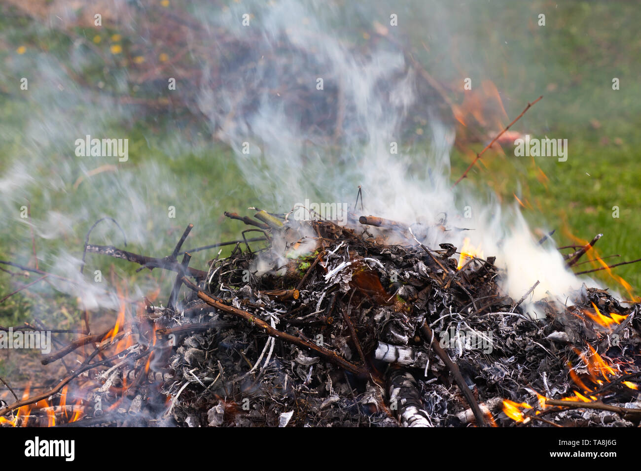 A large pile of burning branches and leaves with smoke Stock Photo - Alamy