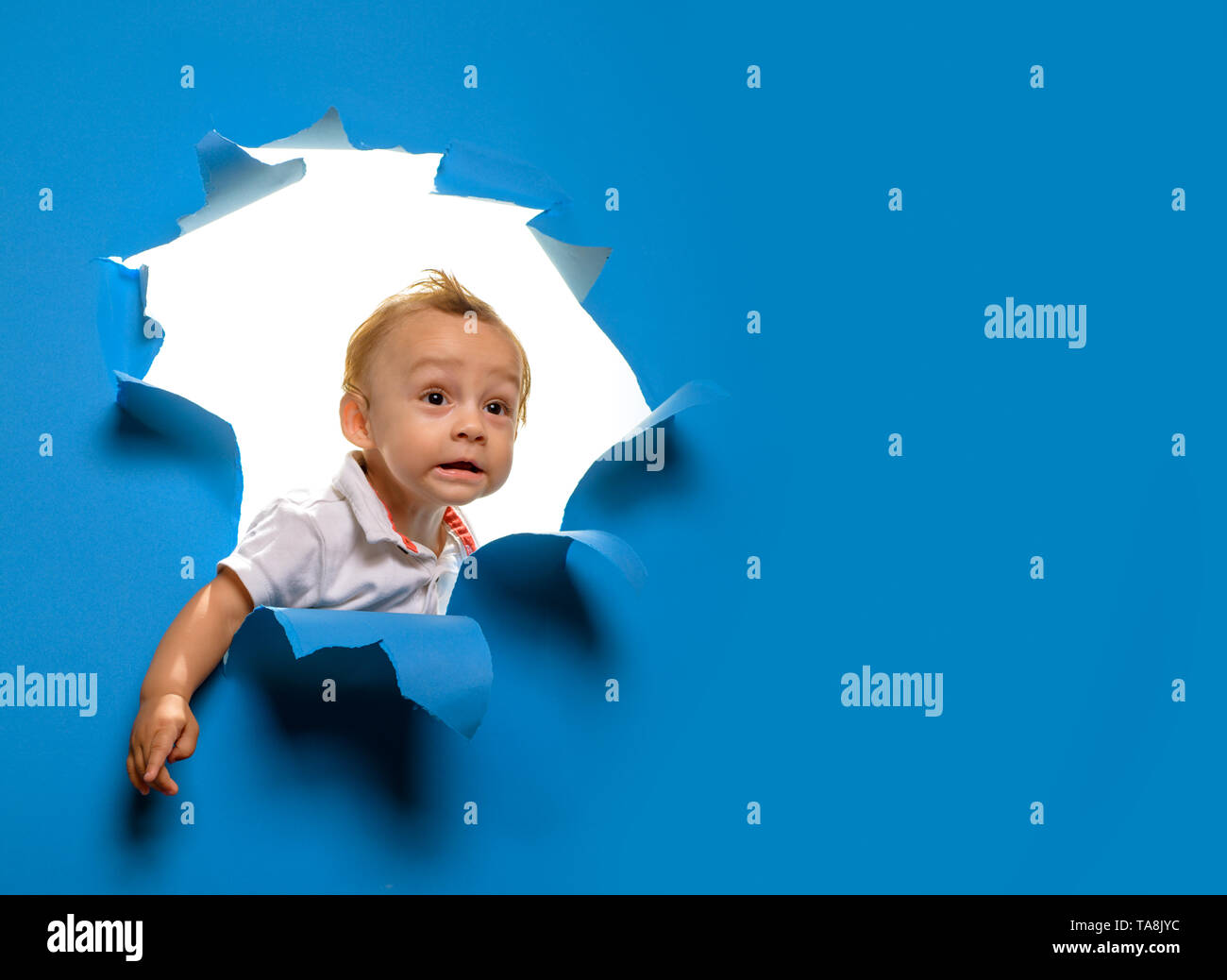 Curious cutie. Little child peek through torn paper. Curious boy child ...