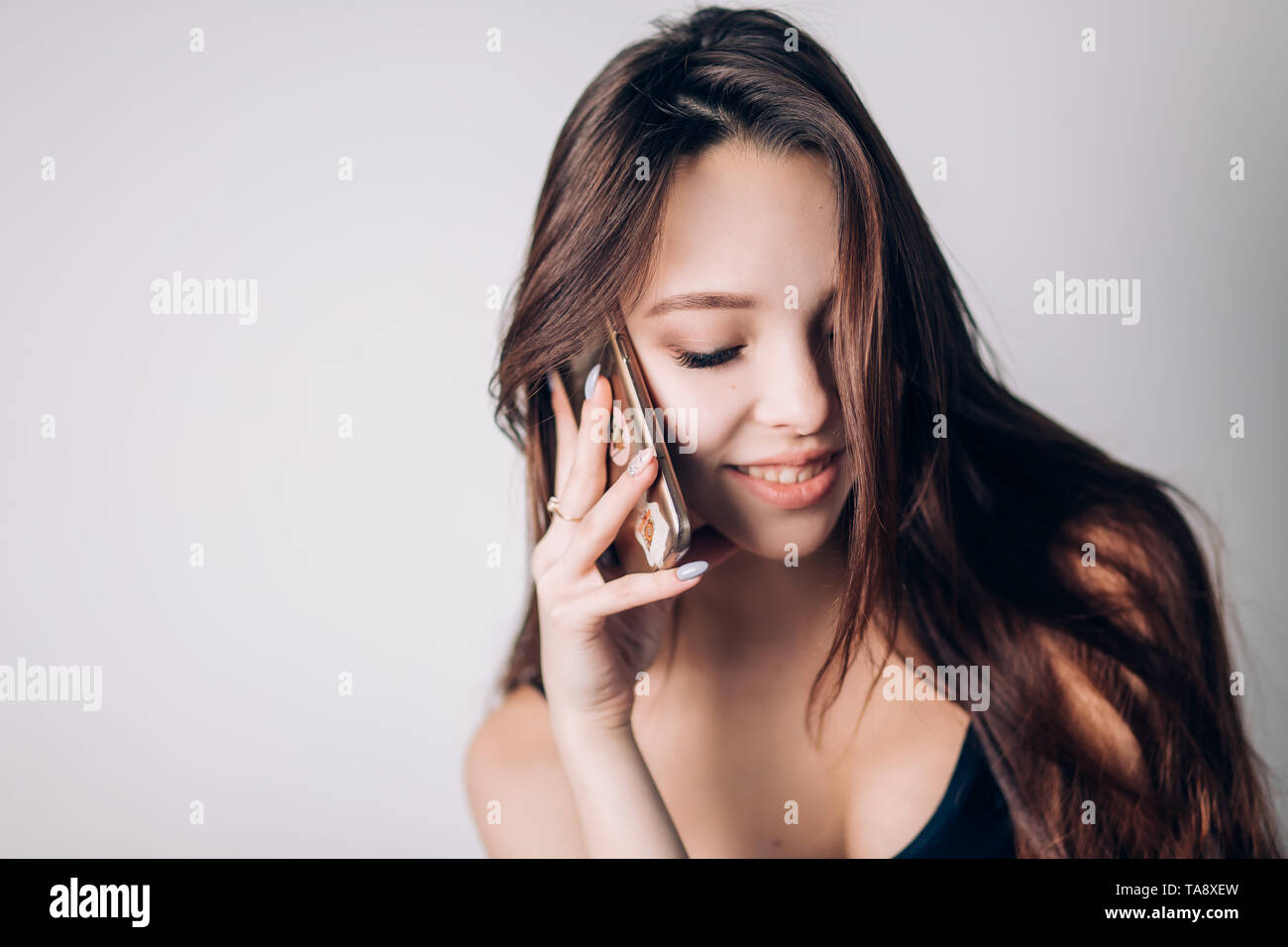 Girl calling on phone. Beautiful woman uses a smartphone on a white ...