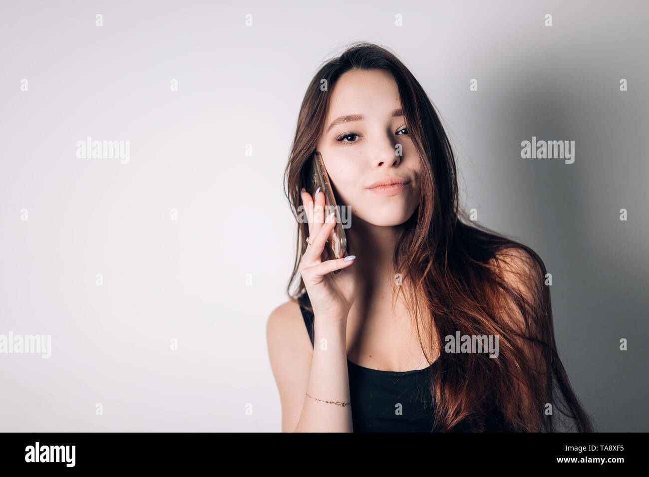 Girl calling on phone. Beautiful woman uses a smartphone on a white ...