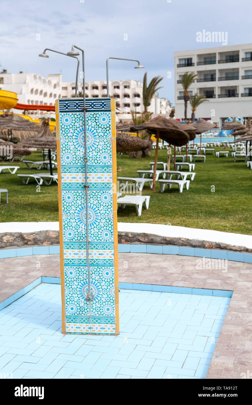 Three units shower is on sunbathing area of hotel, green grass and ...