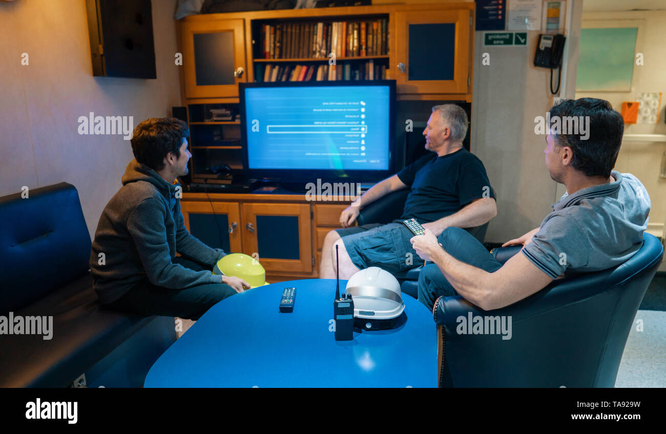 Happy team of ship officers watch TV onboard of vessel Stock Photo - Alamy