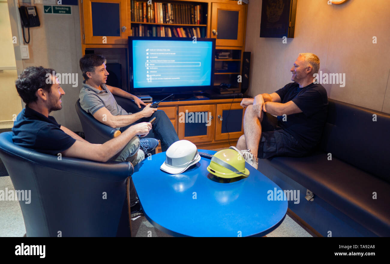 Happy team of ship officers watch TV onboard of vessel Stock Photo - Alamy