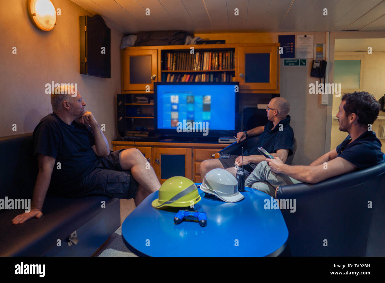Happy team of ship officers watch TV onboard of vessel Stock Photo - Alamy
