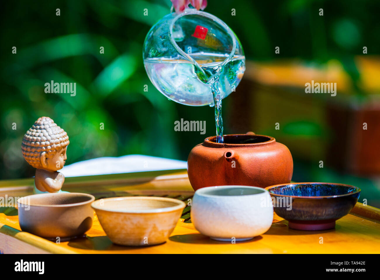 On the table on a wooden tray a teapot with tea, teapot, cups. Man ...