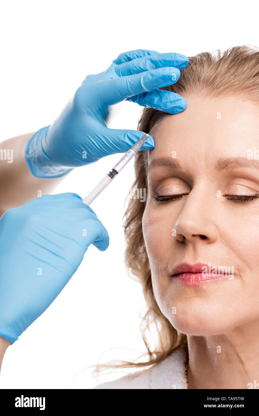 doctor giving beauty injection to middle aged woman with closed eyes ...