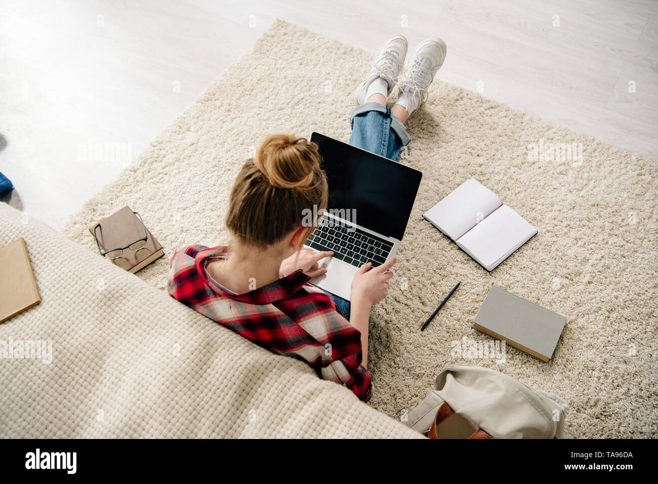 Overhead view of teenager with books and laptop with blank screen doing ...