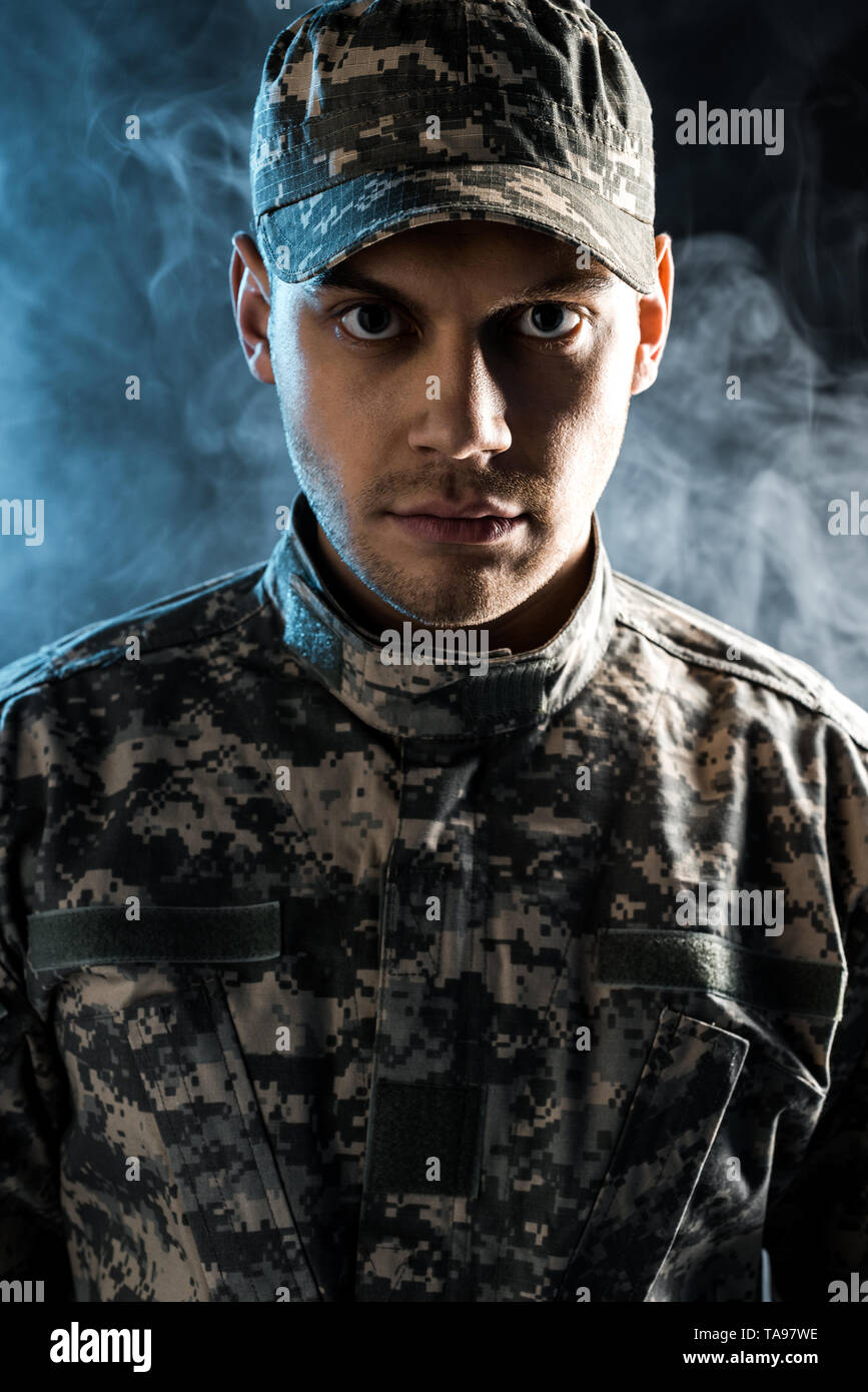 confident soldier in military cap and uniform looking at camera on ...