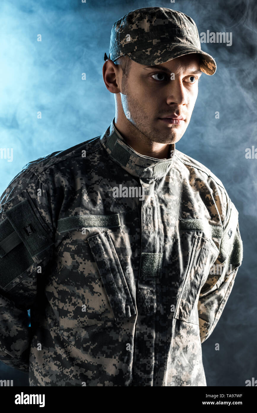 confident soldier in military cap and uniform on black with smoke Stock ...
