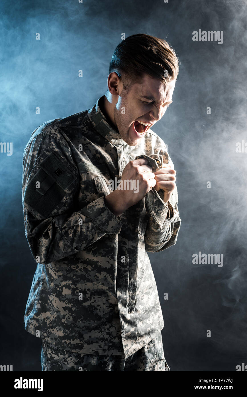 emotional man in military uniform screaming on black with smoke Stock ...
