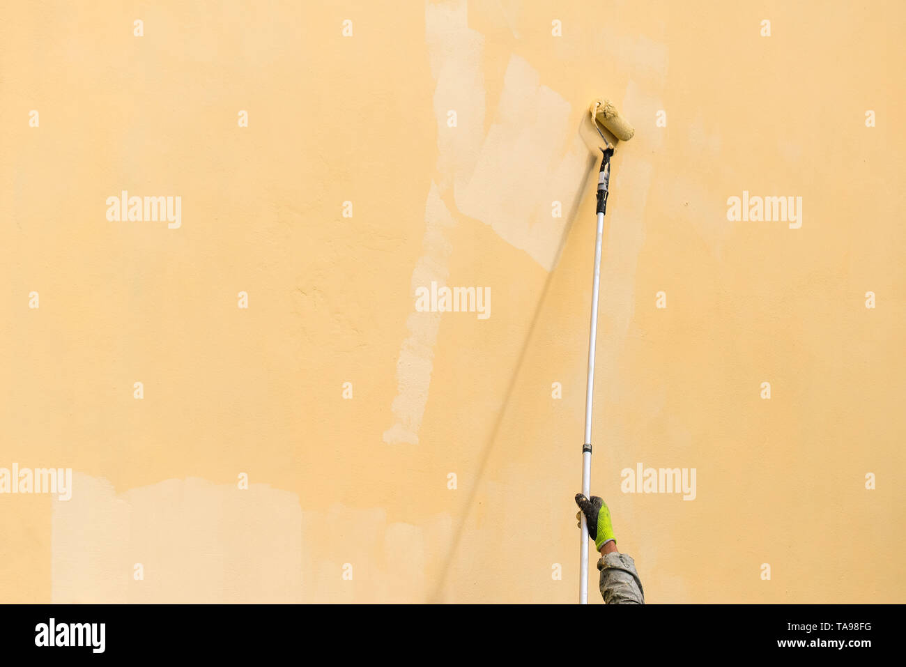 Painter paints building exterior wall with a roller. Roller with long ...