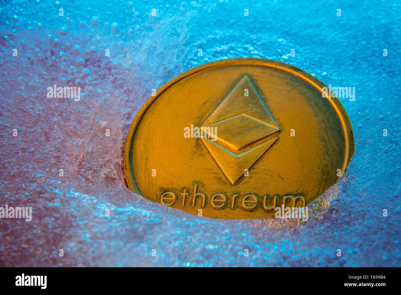 Golden Ethereum coin, online digital currency frozen in the blue ice ...